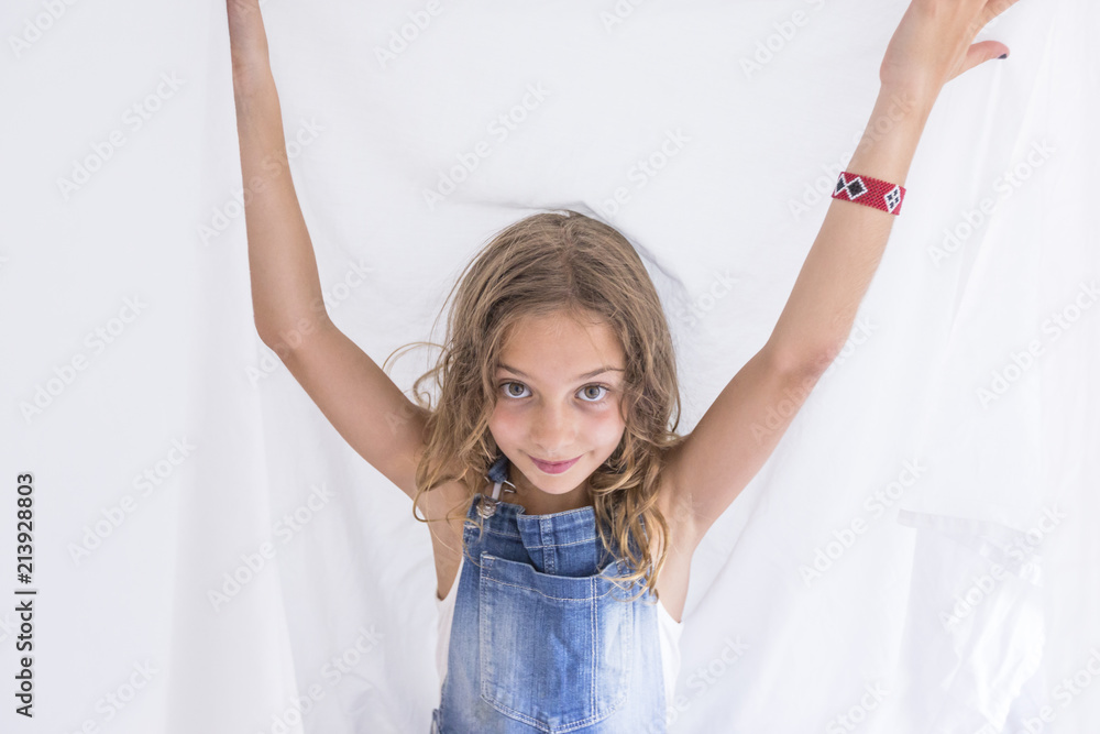 beautiful kid girl playing under white sheets on bed. Fun indoors ...
