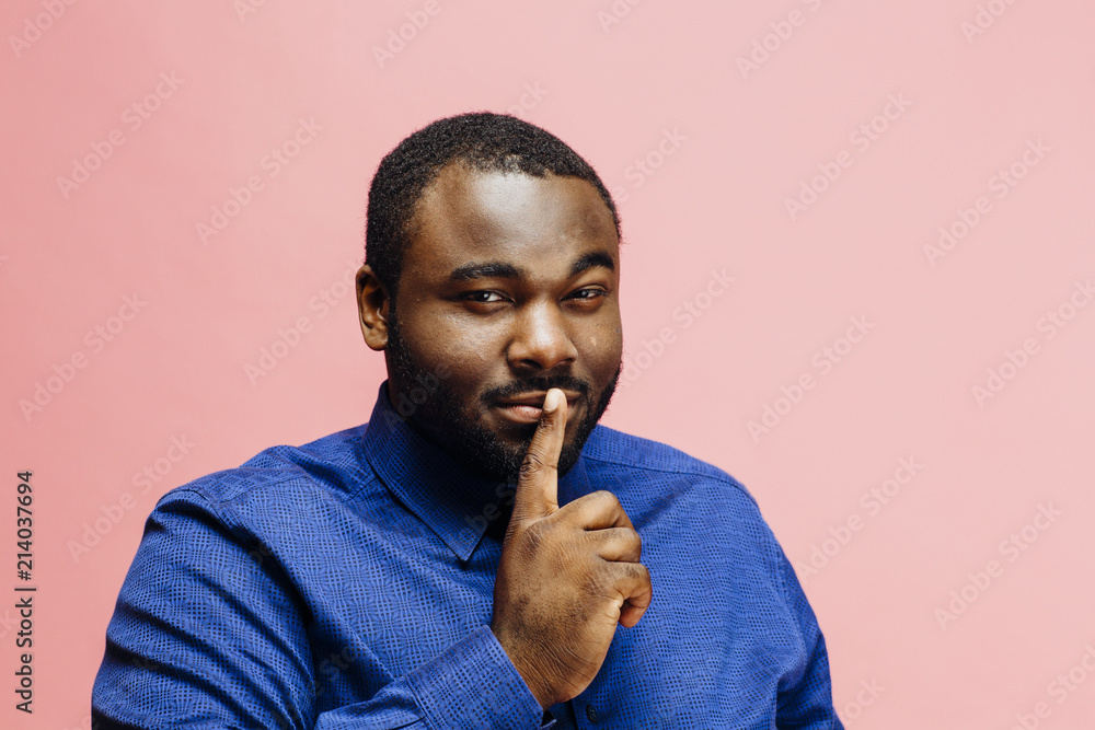 Don't tell anyone! Young man in blue shirt holding finger over his ...