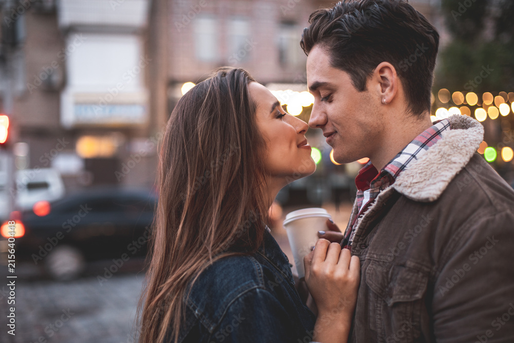Profile of delighted male and woman standing in cuddles outdoors. They ...