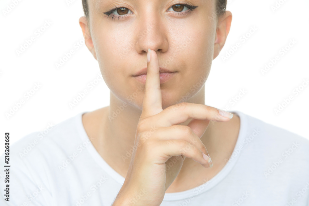 Secretive young woman placing finger on lips asking shh, quiet, silence ...
