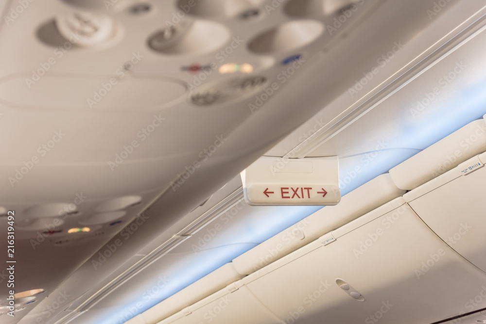 Emergency exit sign with red arrow on ceiling of airplane. Illuminated ...