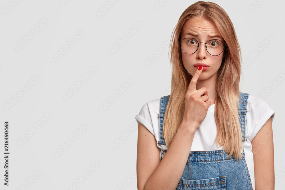 Surprised attractive female model has shocked expression, keeps finger ...