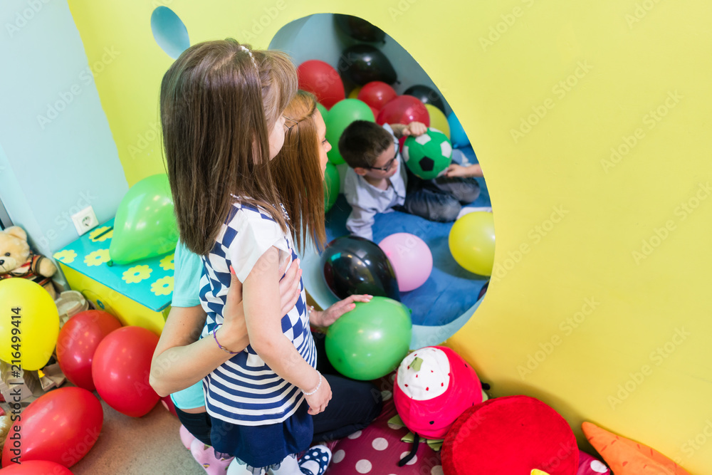 Caring young female teacher holding and guiding a shy pre-school girl ...