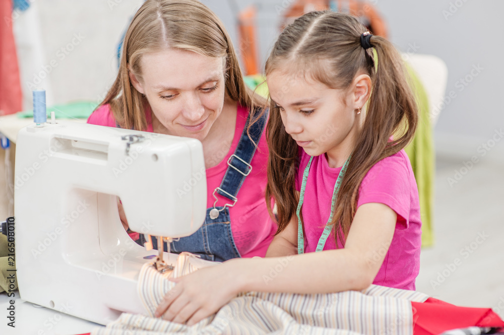 Mother teaches a little girl to sew on a sewing machine Stock Photo ...