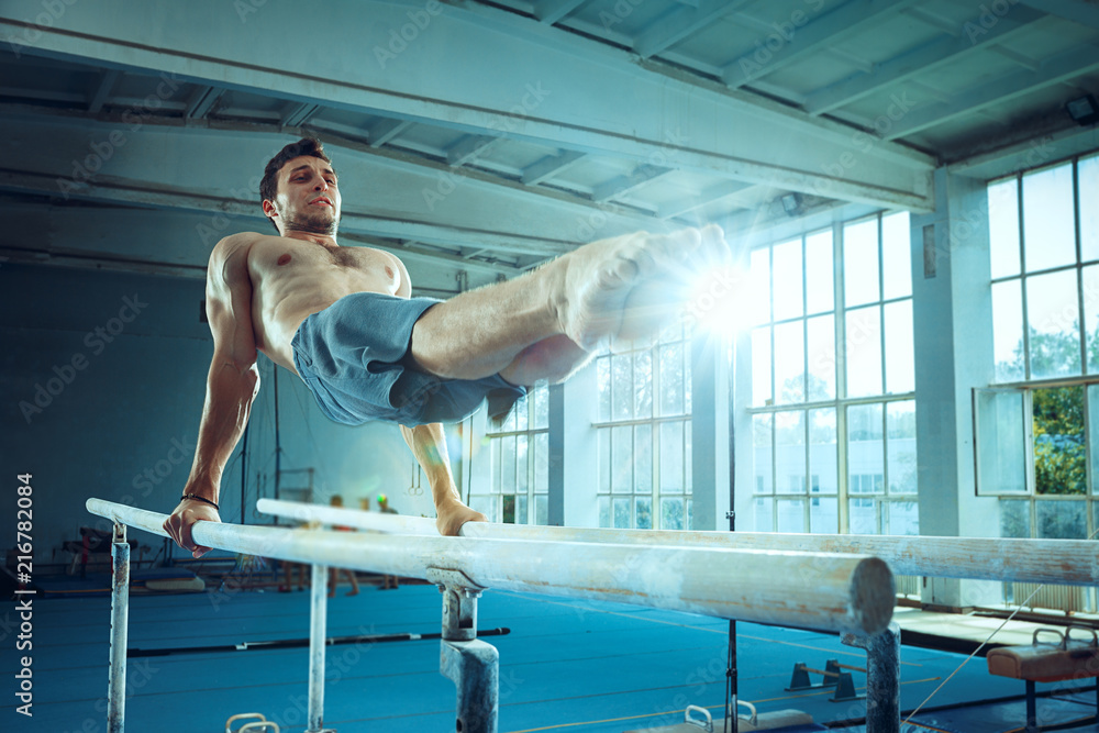 The sportsman performing difficult gymnastic exercise at gym. The sport ...