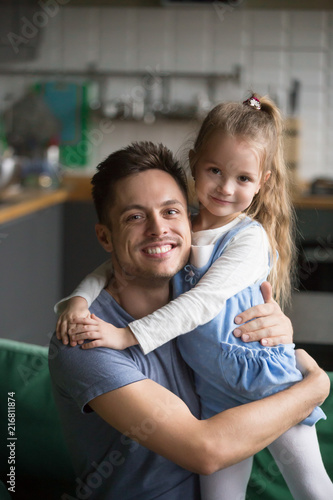 Vertical portrait of happy kid daughter embracing father at home, cute ...