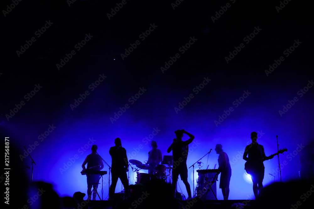 music band playing on concert stage, silhouettes of musicians ...