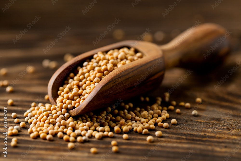 Heap of raw, unprocessed mustard seed kernels in wooden scoop on rustic ...