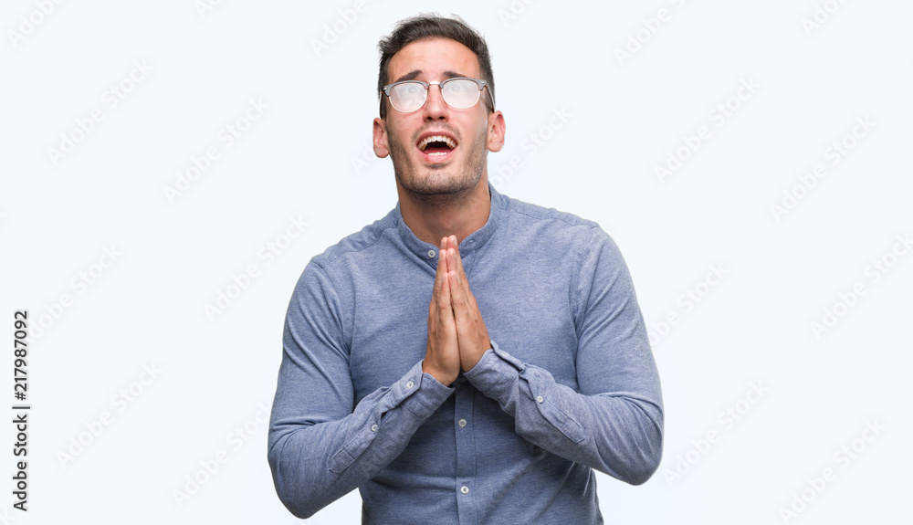 Handsome young elegant man wearing glasses begging and praying with ...