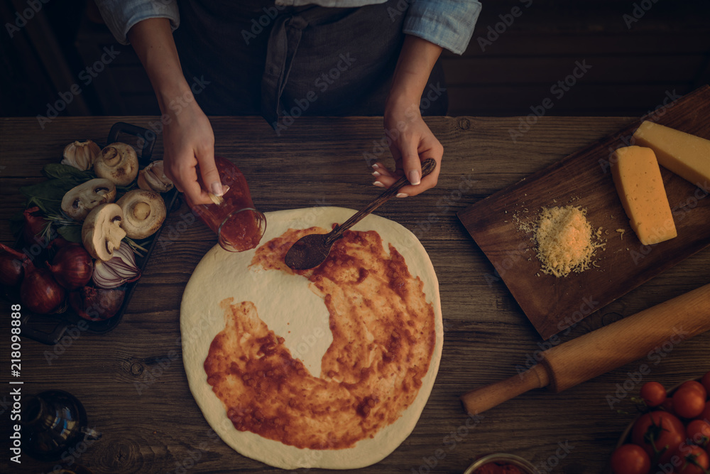 The process of making pizza. Prepare dough hand topping. Woman hand is ...