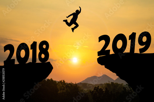Happy new year Silhouette sunset background. A man jumping over cliff ...