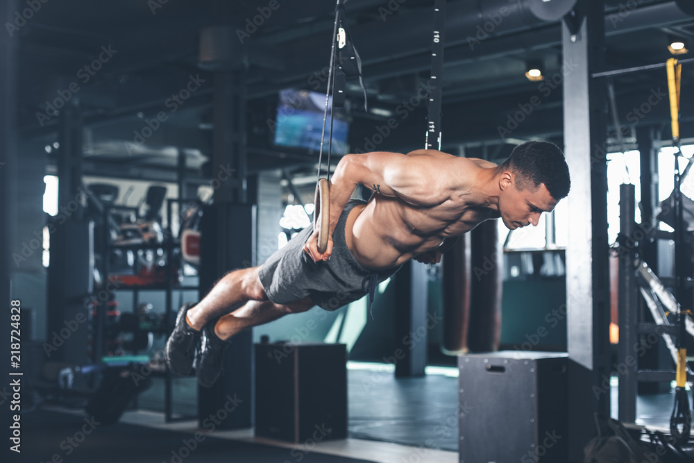 Foto Shredded guy is feeling tension while exercising with gymnastic ...
