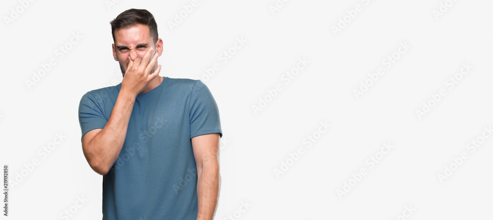Handsome young casual man smelling something stinky and disgusting ...