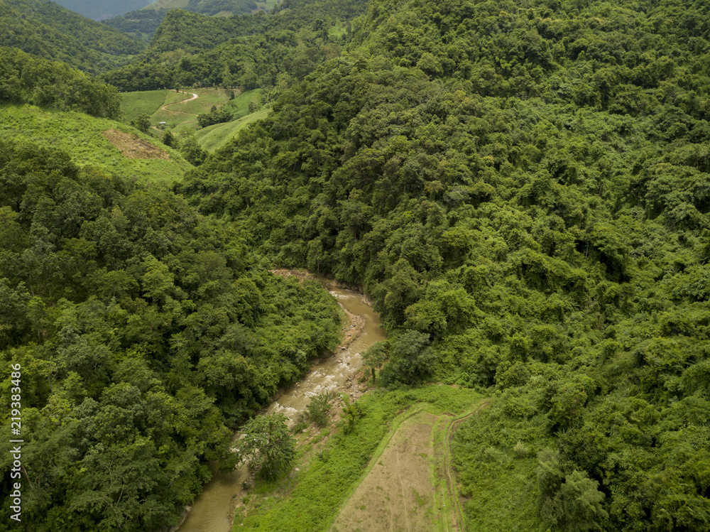 Aerial view of a village in the lush green rain cloud cover tropical ...