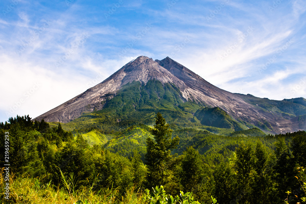 Scenic cone volcano with azure blue sky and clouds and green rainforest ...