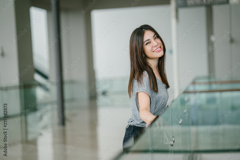 A young Japanese woman leans against the glass railing in a clean ...