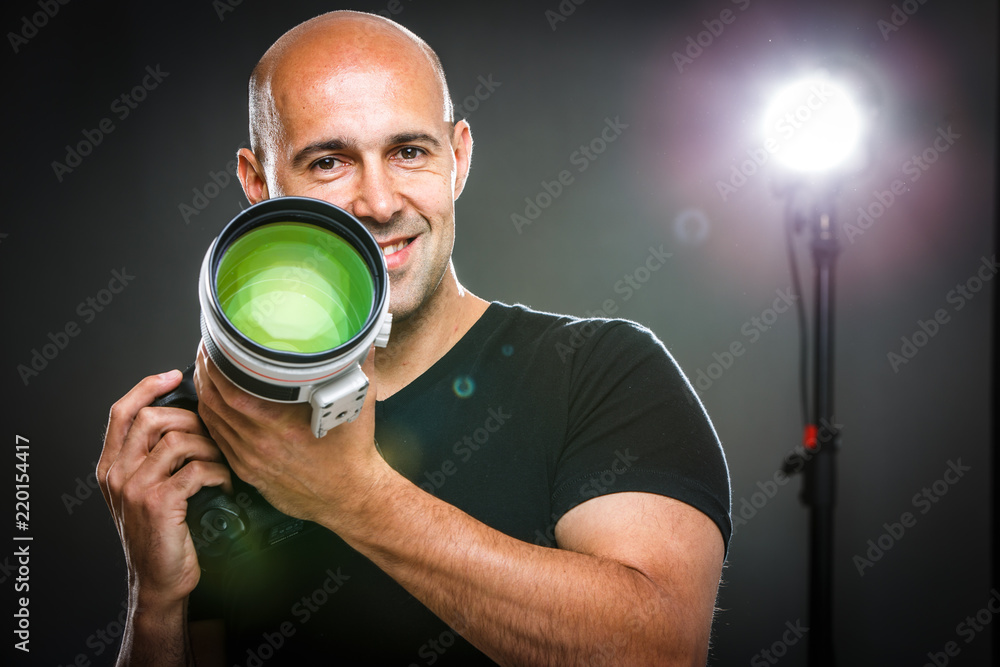 Young, pro male photographer in his studio during a photo shoot (color ...