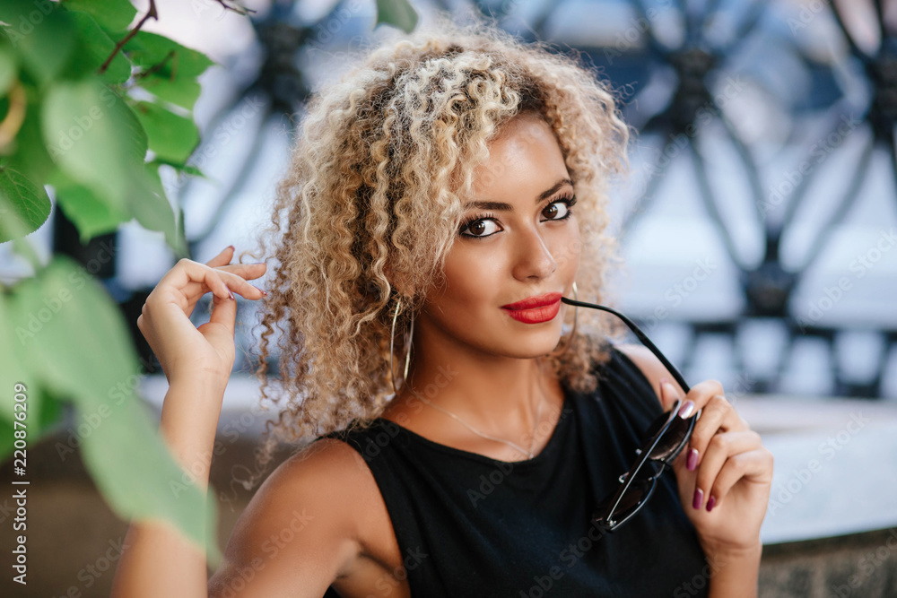 Young mixed woman with afro hairstyle smiling in urban background ...