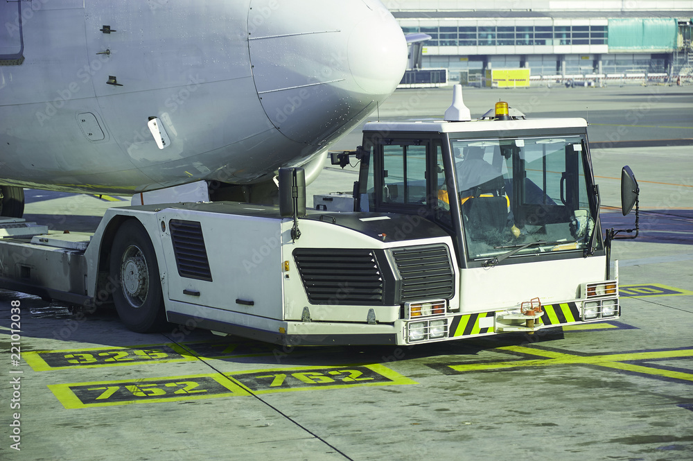 Large aircraft being pulled by airport tug tractor taxing on airfield ...