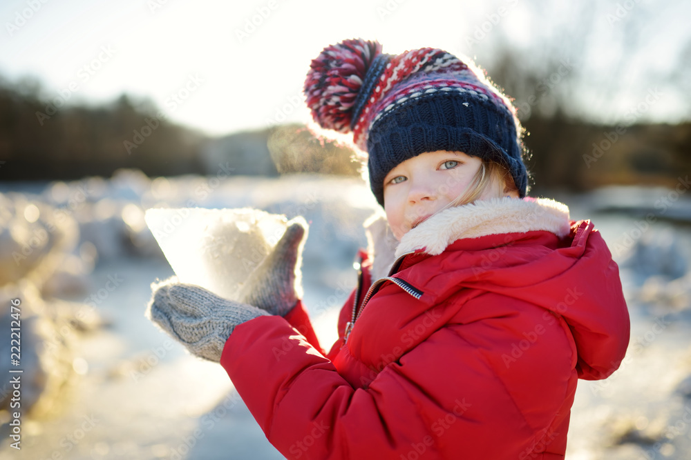 Photo Stock Happy little girl playing with ice blocks by frozen river ...