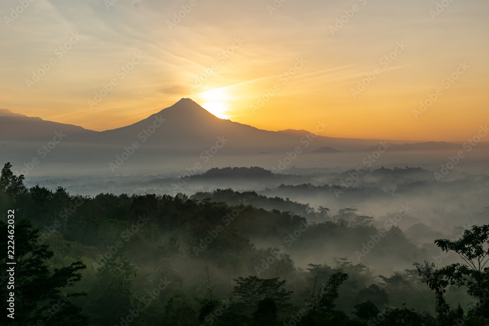Scenic view of sunrise behind Merapi volcano, misty jungle and ...