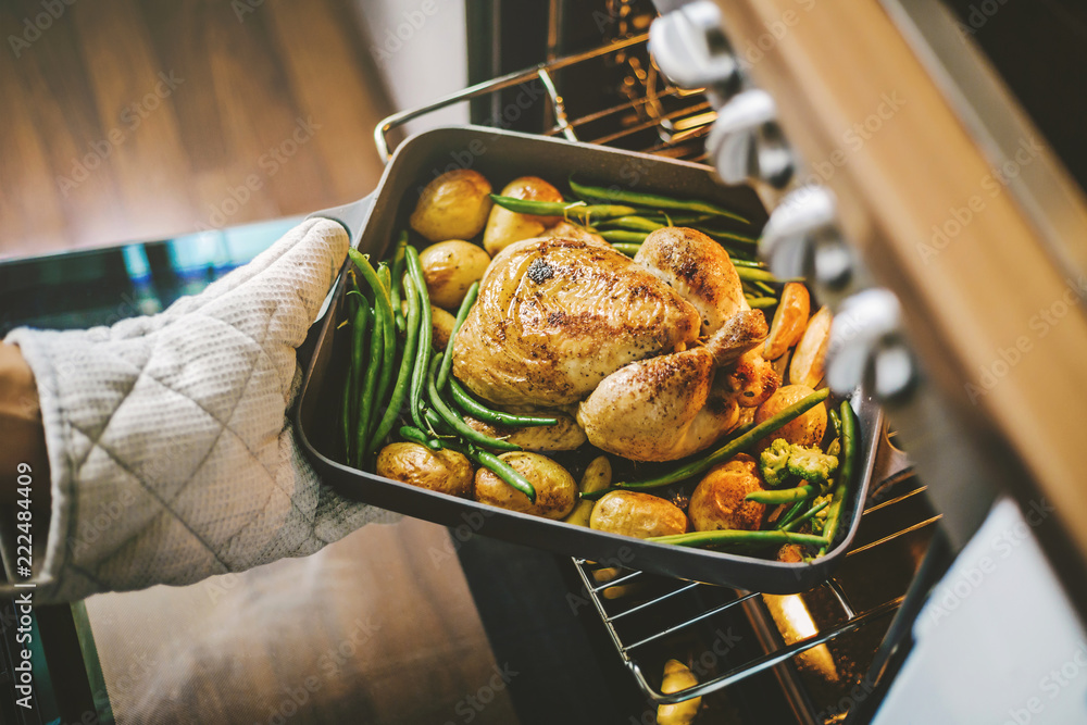 Cook taking ready chicken from the oven Stock Photo | Adobe Stock
