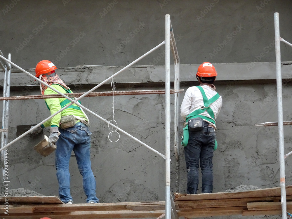 Brick wall plastered by construction workers using the cement plaster ...
