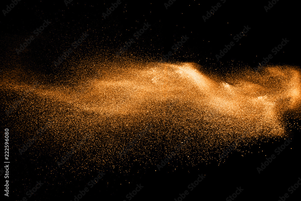 orange dust particles explosion on black background. Color powder dust ...