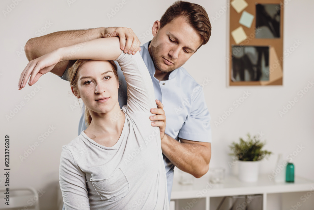 Physiotherapist supporting patient with shoulder pain during ...