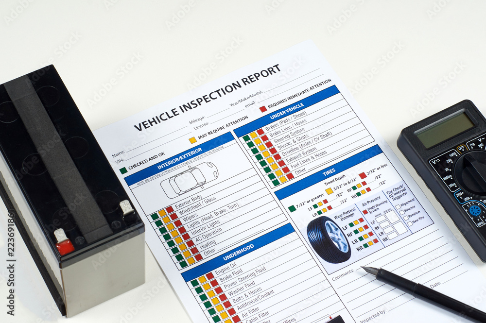 Vehicle inspection report form with multimeter, pen and battery on ...