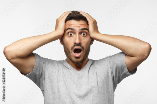 Shock content. Surprised young male in gray t-shirt shouting, holding ...