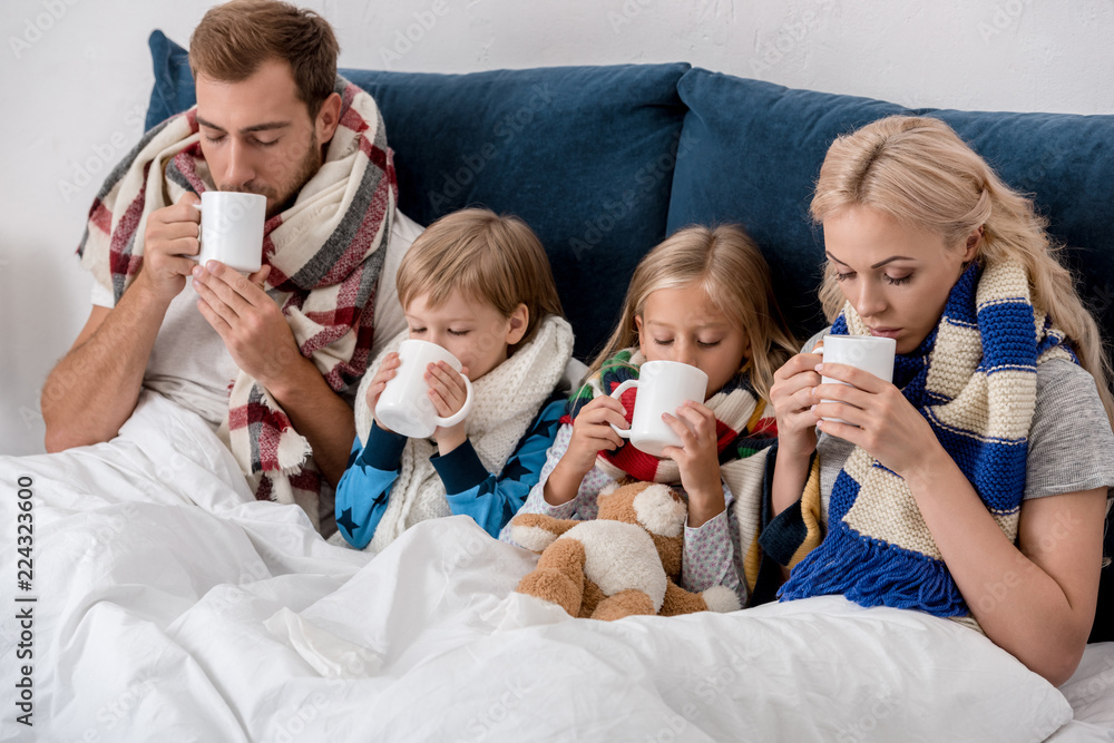 sick young family drinking warming beverages while sitting in bed Stock ...