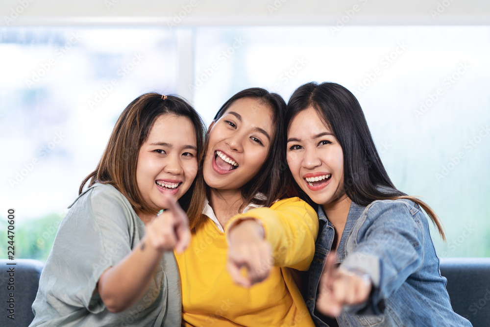 Young attractive asian women or three best friends sitting and pointing ...