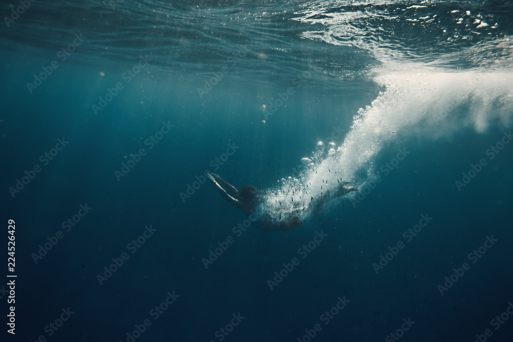 Underwater swimmer in sea with air jet bubbles tail against dark water ...