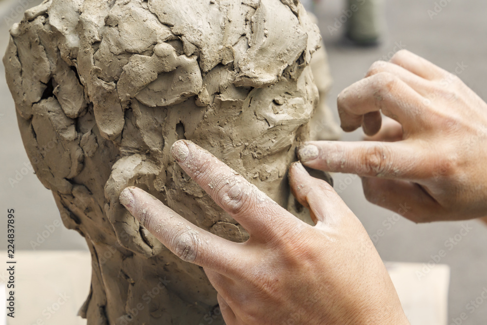 sculptor creates a bust and puts his hands clay on the skeleton of the ...