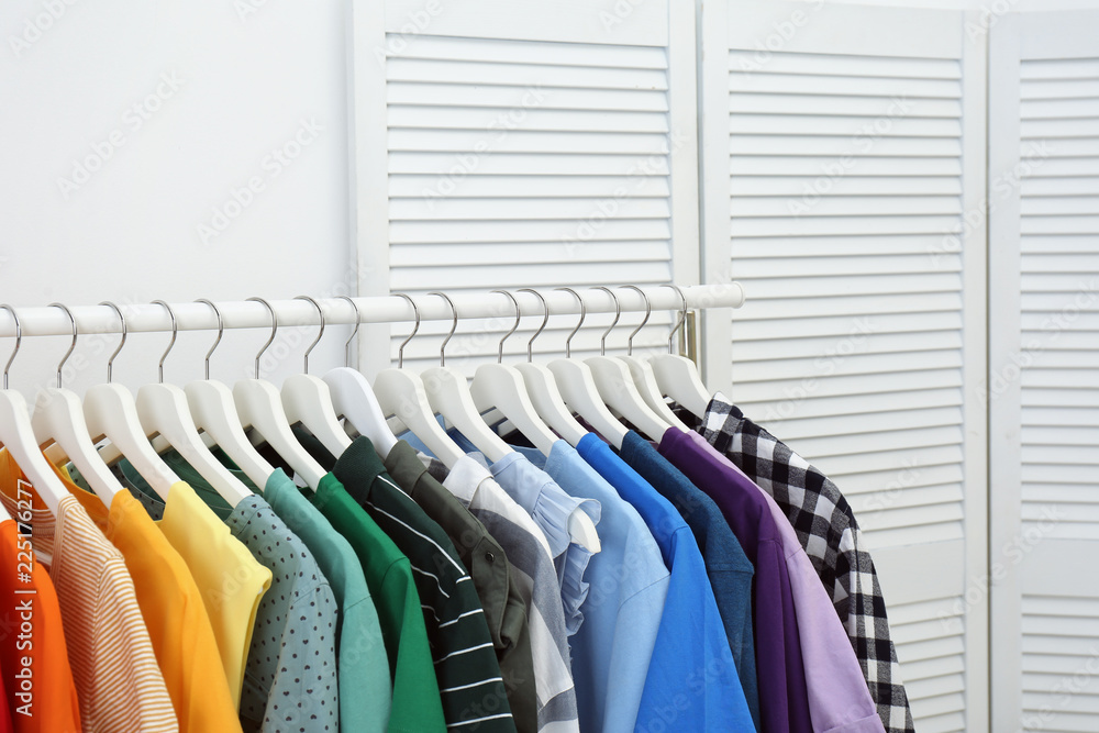 Rack with bright clothes in room. Rainbow colors Stock Photo | Adobe Stock