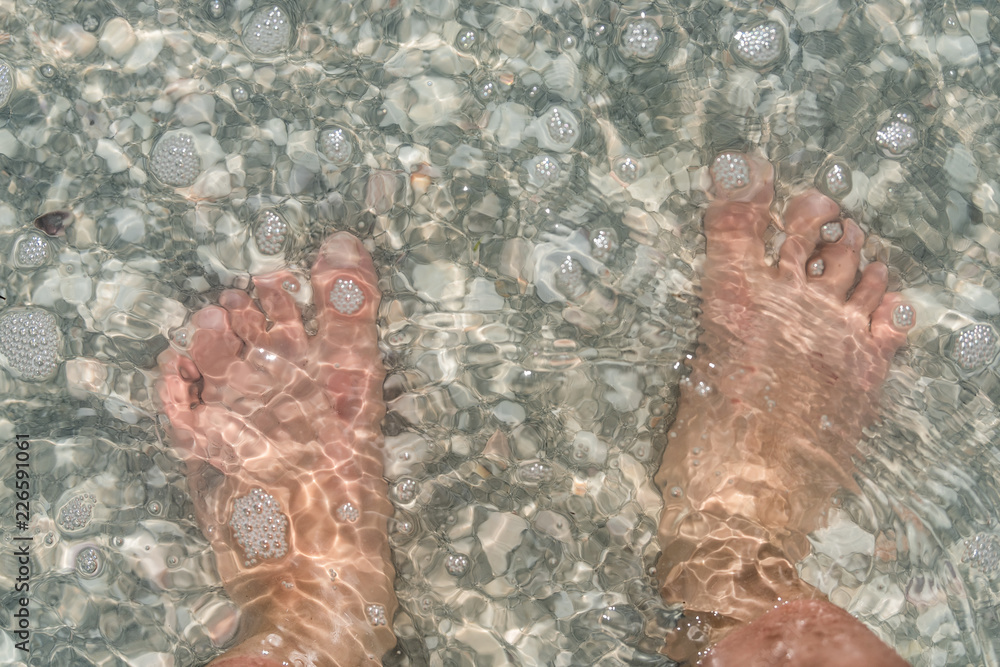 Flat top view down of woman's bare feet under shallow green Florida ...