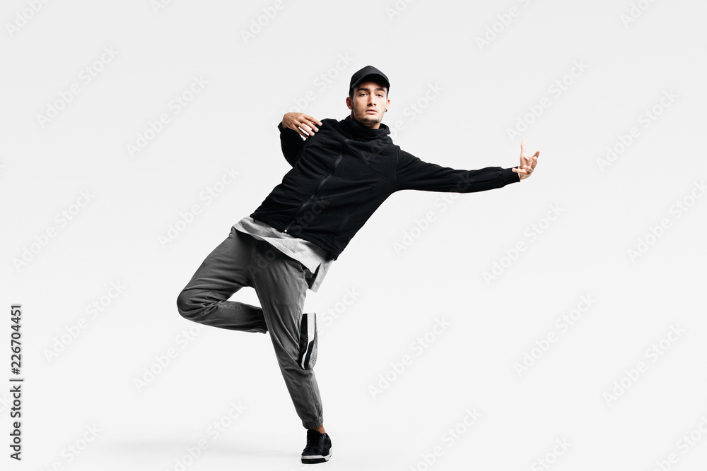 Handsome young man wearing a black sweatshirt, gray pants and a cap ...