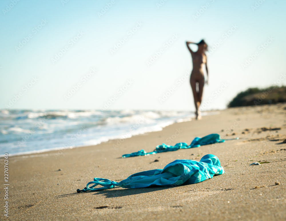 Swimsuit In The Sand On The Beach Near The Sea Surf On The Background