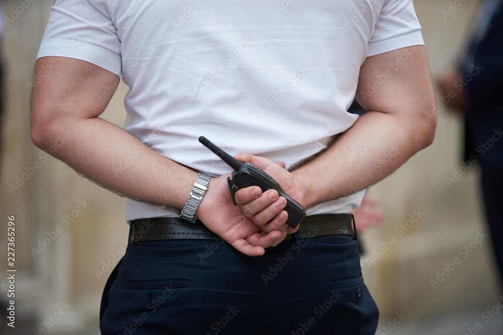 Bodyguard holding Portable radio transceiver in hand. Security Guard ...