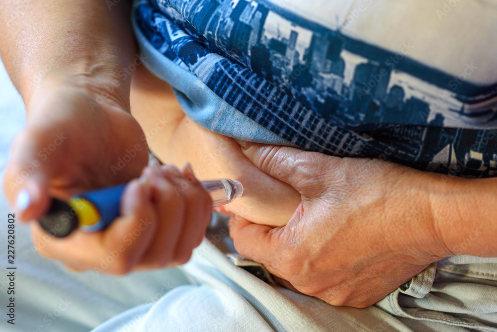 Elderly woman giving herself injection in abdomen against pain and ...