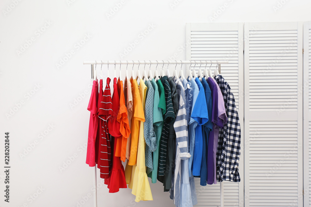 Rack with bright clothes in room. Rainbow colors Stock Photo | Adobe Stock