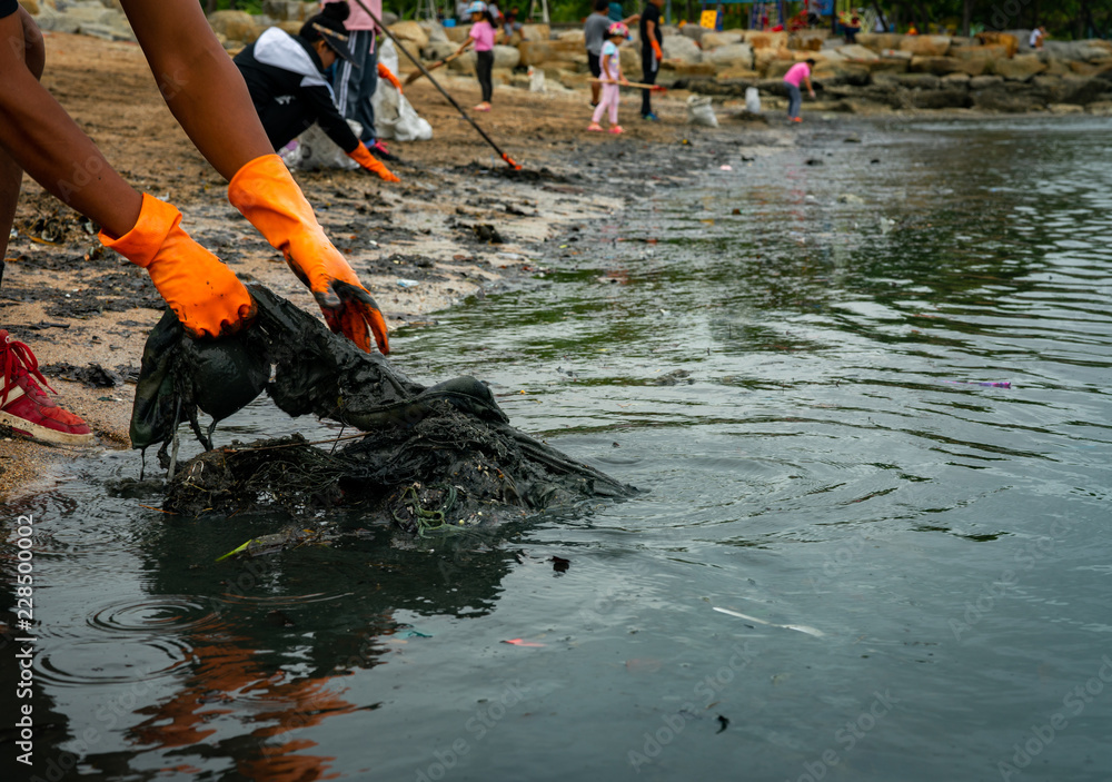 Fotografie Volunteers wear orange rubber gloves to collect garbage on ...