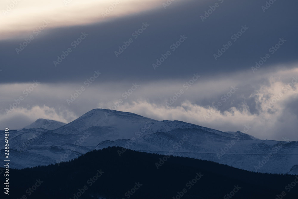 Dramatic winter storm blows over a cold barren landscape at sunset ...