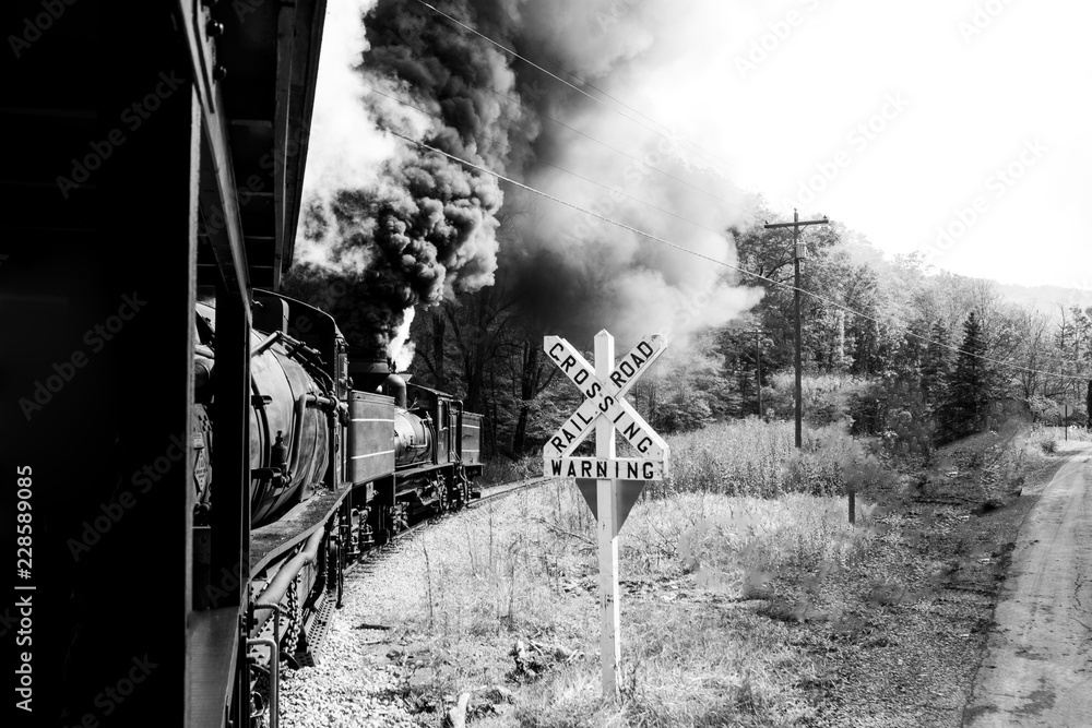 Steam locomotive rounding a bend at a railroad crossing with a giant ...