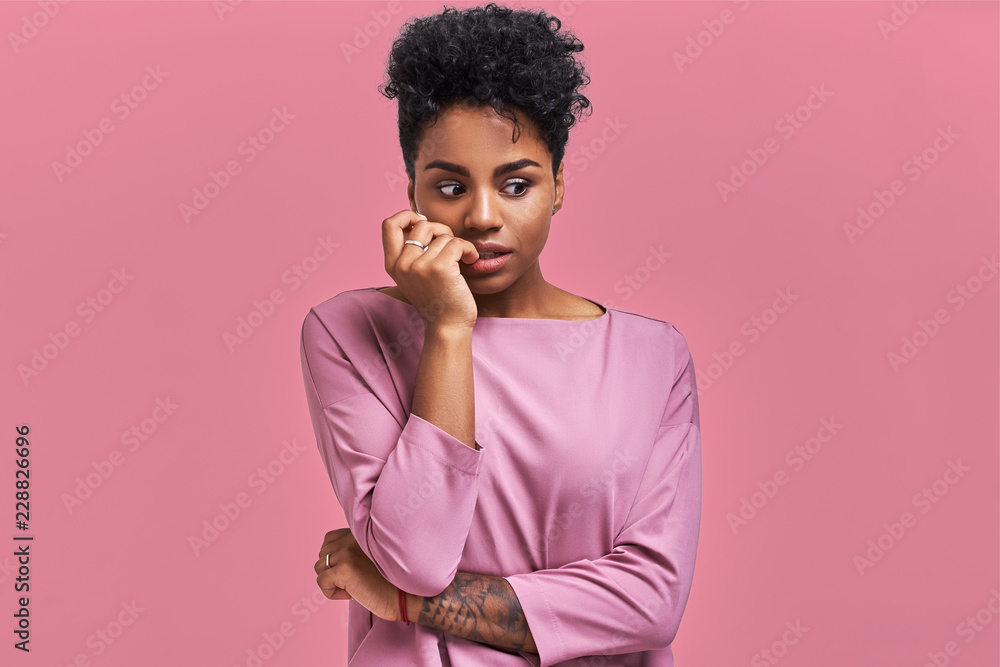 Embarrassed African American woman pursed lips, looks with puzzlement ...