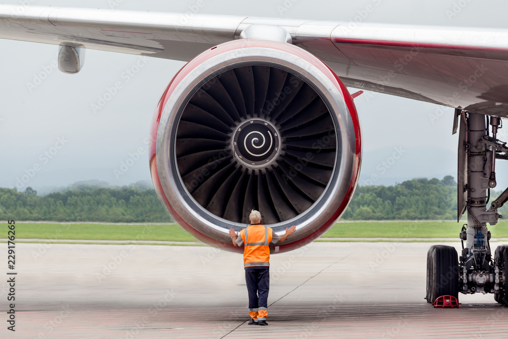 Engineer checks turbine engine of modern passenger airplane on runway ...