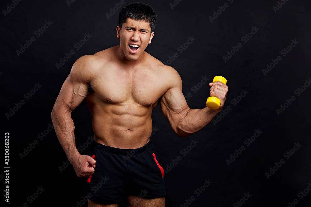 shouting angry athlete holding dumbbell and looking a the camera ...