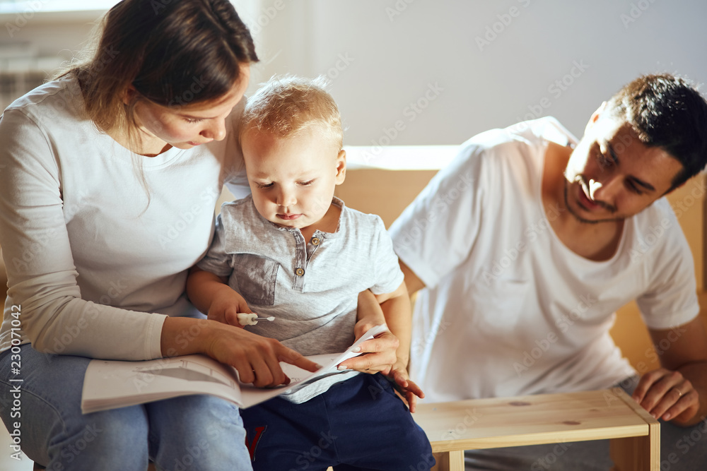 family with little boy reading instruction and assemble furniture ...