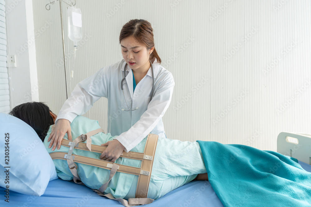 Attractive Asian female doctor help or wearing back support for protect ...